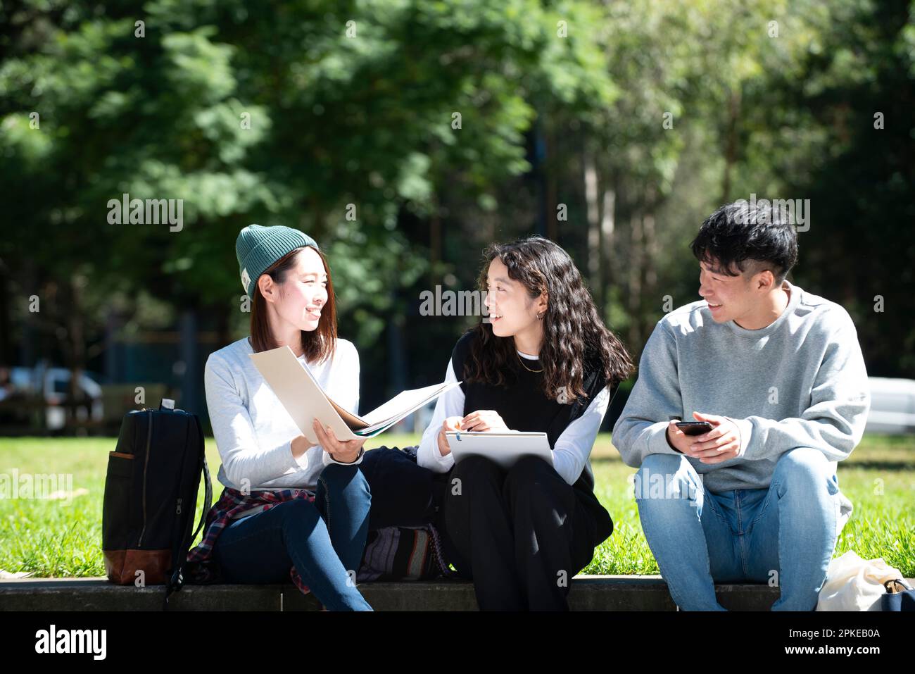 Three students talking outside with notebooks spread out Stock Photo ...