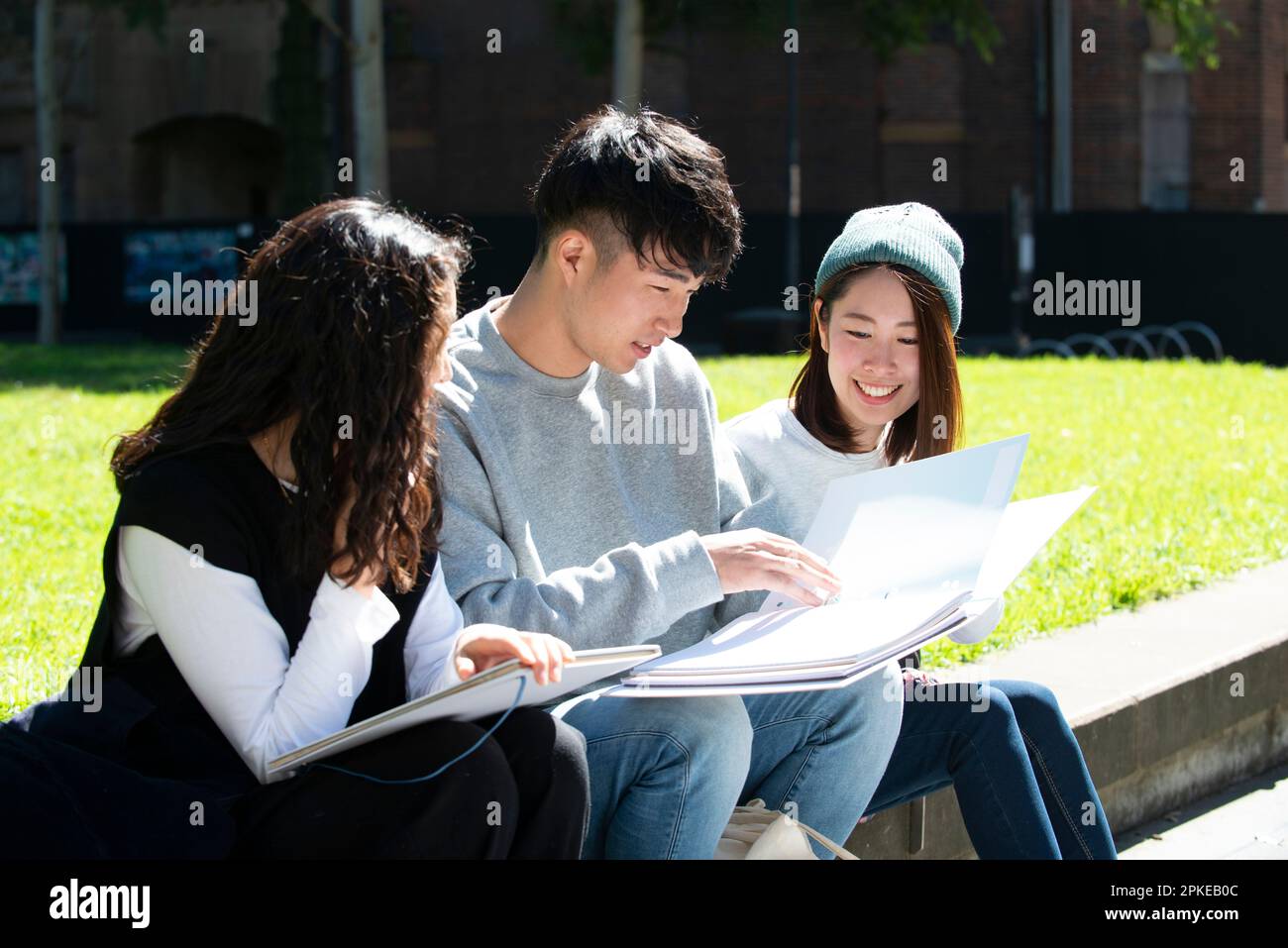 Three students talking outside with notebooks spread out Stock Photo ...