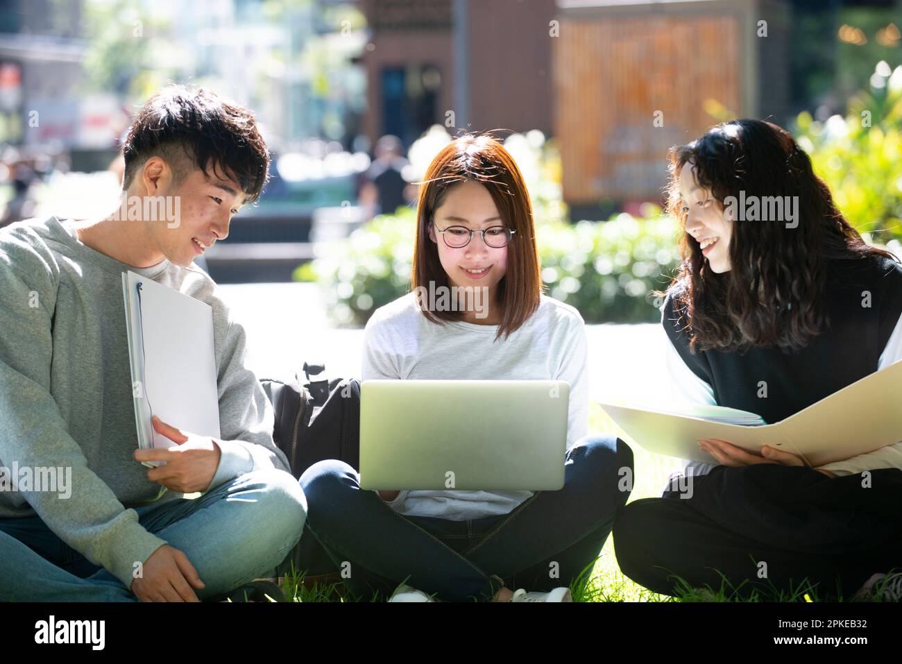 Three students studying with computers open outside Stock Photo - Alamy