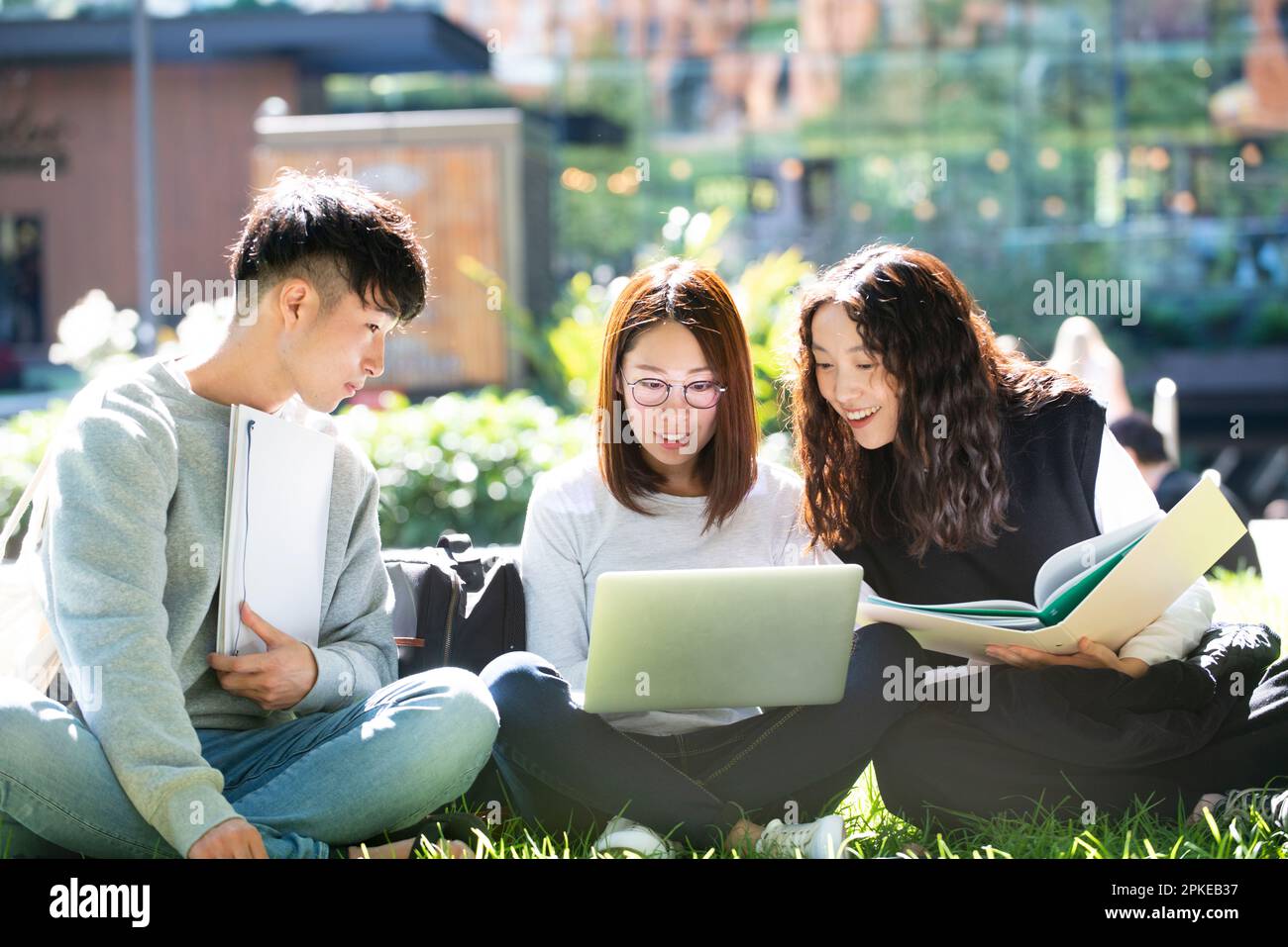 3 students studying with open computer outside Stock Photo - Alamy