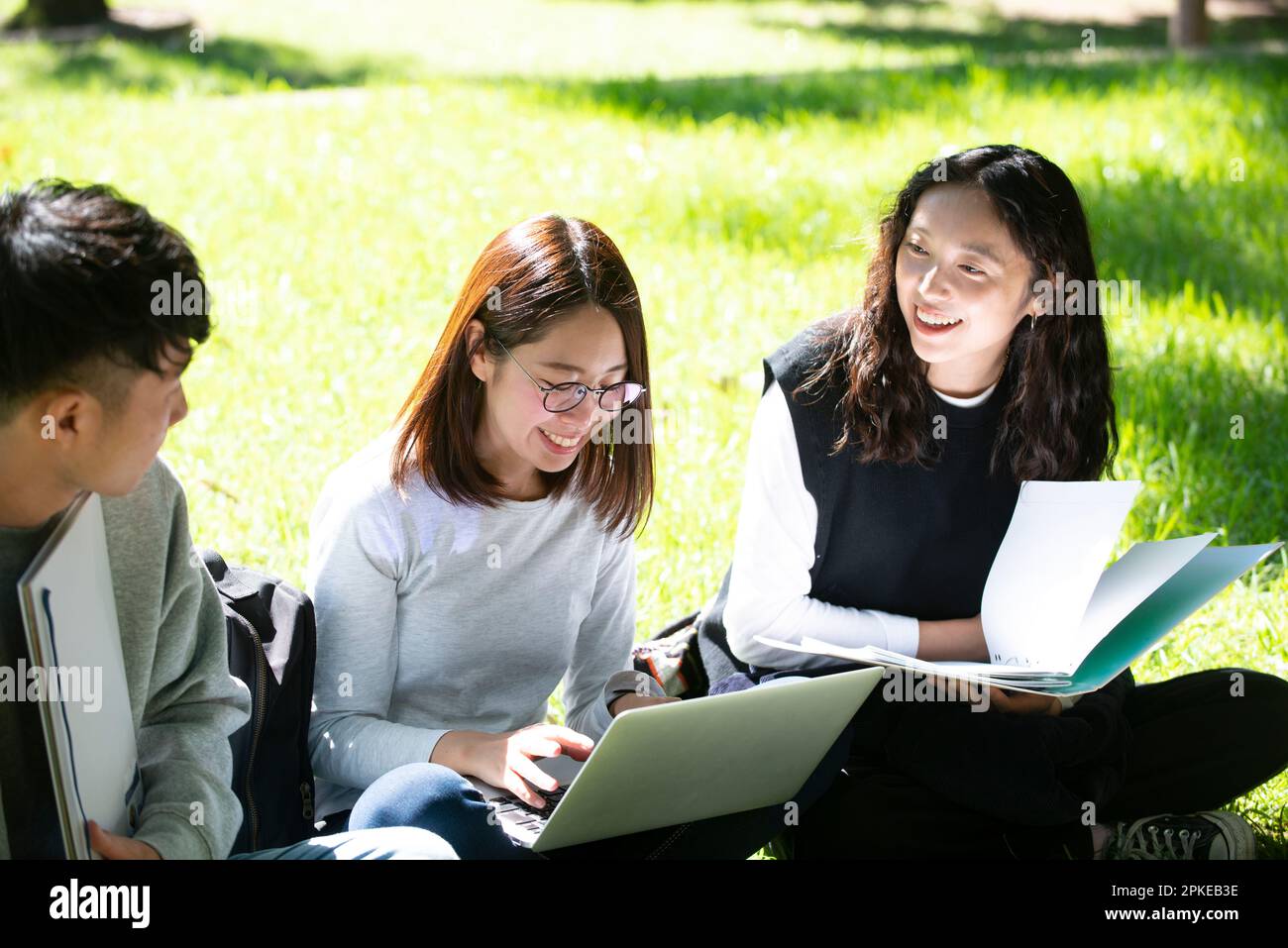 3 students studying with open computer outside Stock Photo - Alamy