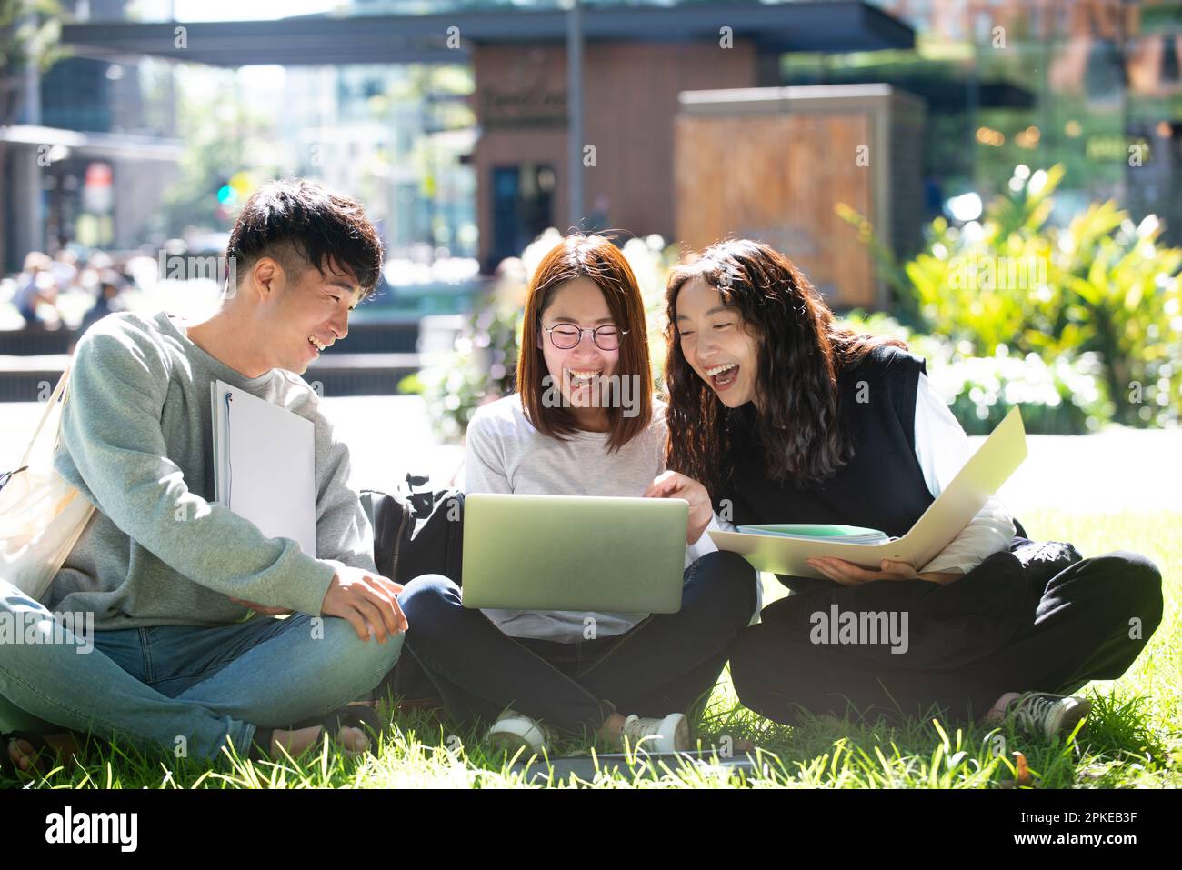 Three students studying with computers open outside Stock Photo - Alamy