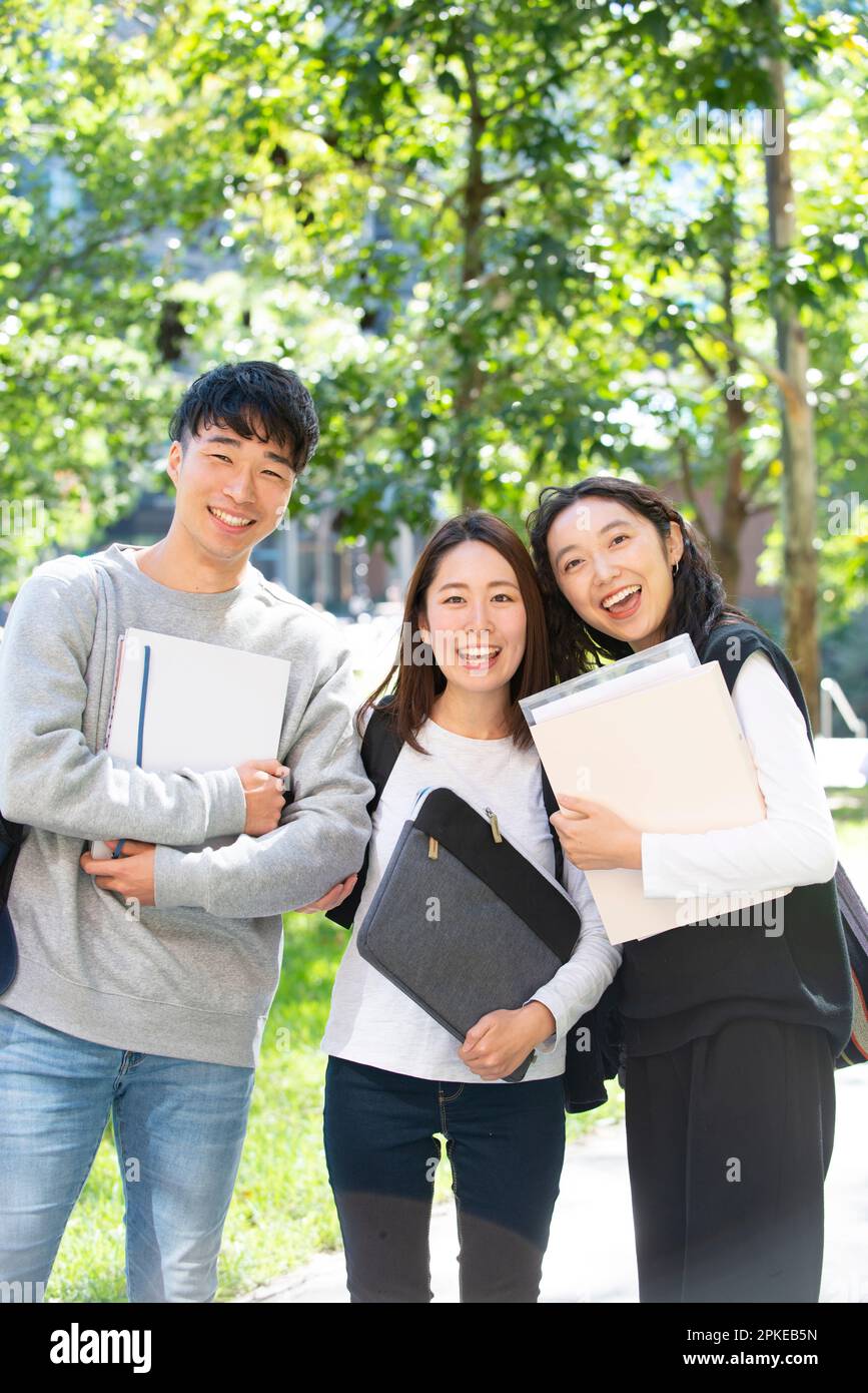 Three students holding notebooks and laughing Stock Photo - Alamy