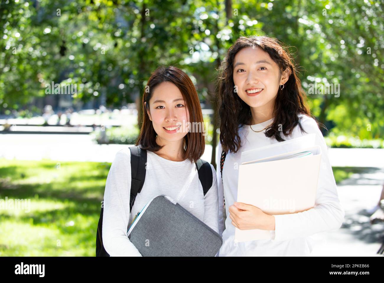 Two female students holding files and laughing Stock Photo - Alamy