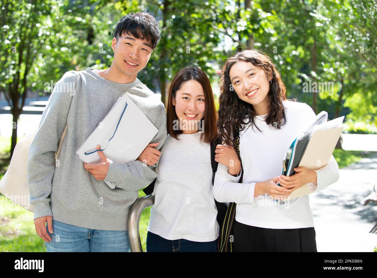 Three students holding files and laughing Stock Photo - Alamy