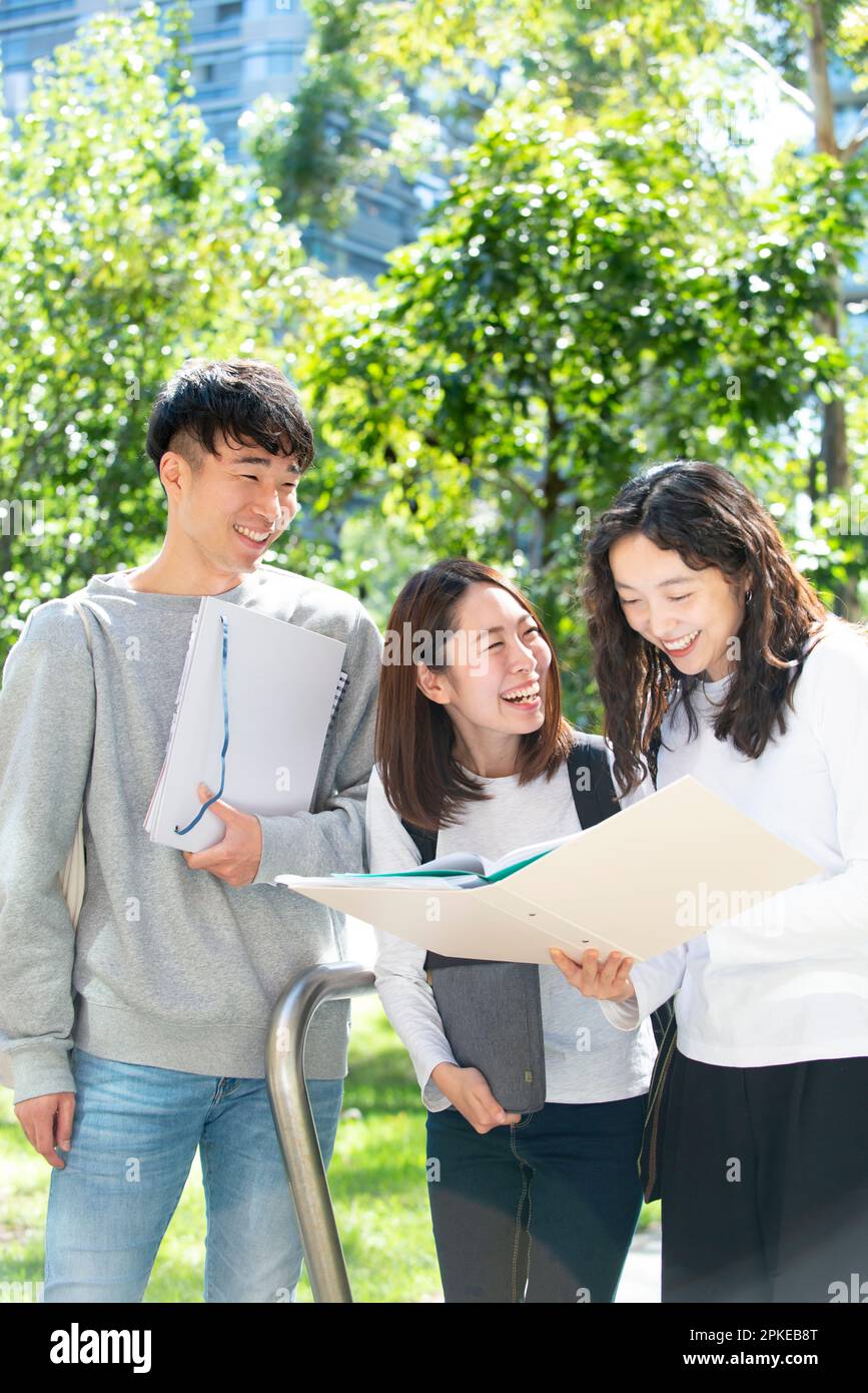 Three students talking with files spread out Stock Photo - Alamy