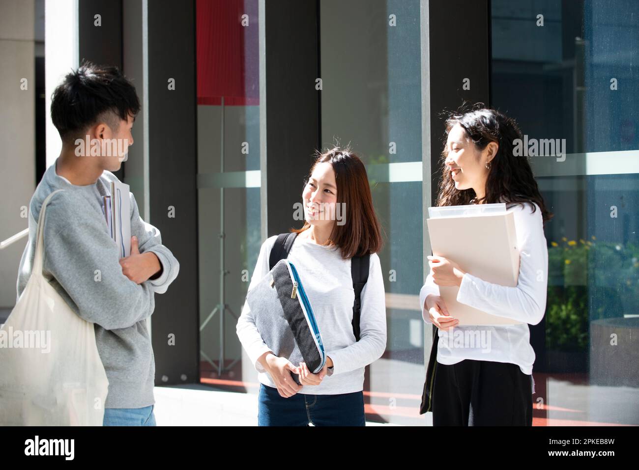 Three students holding and talking about a file Stock Photo - Alamy