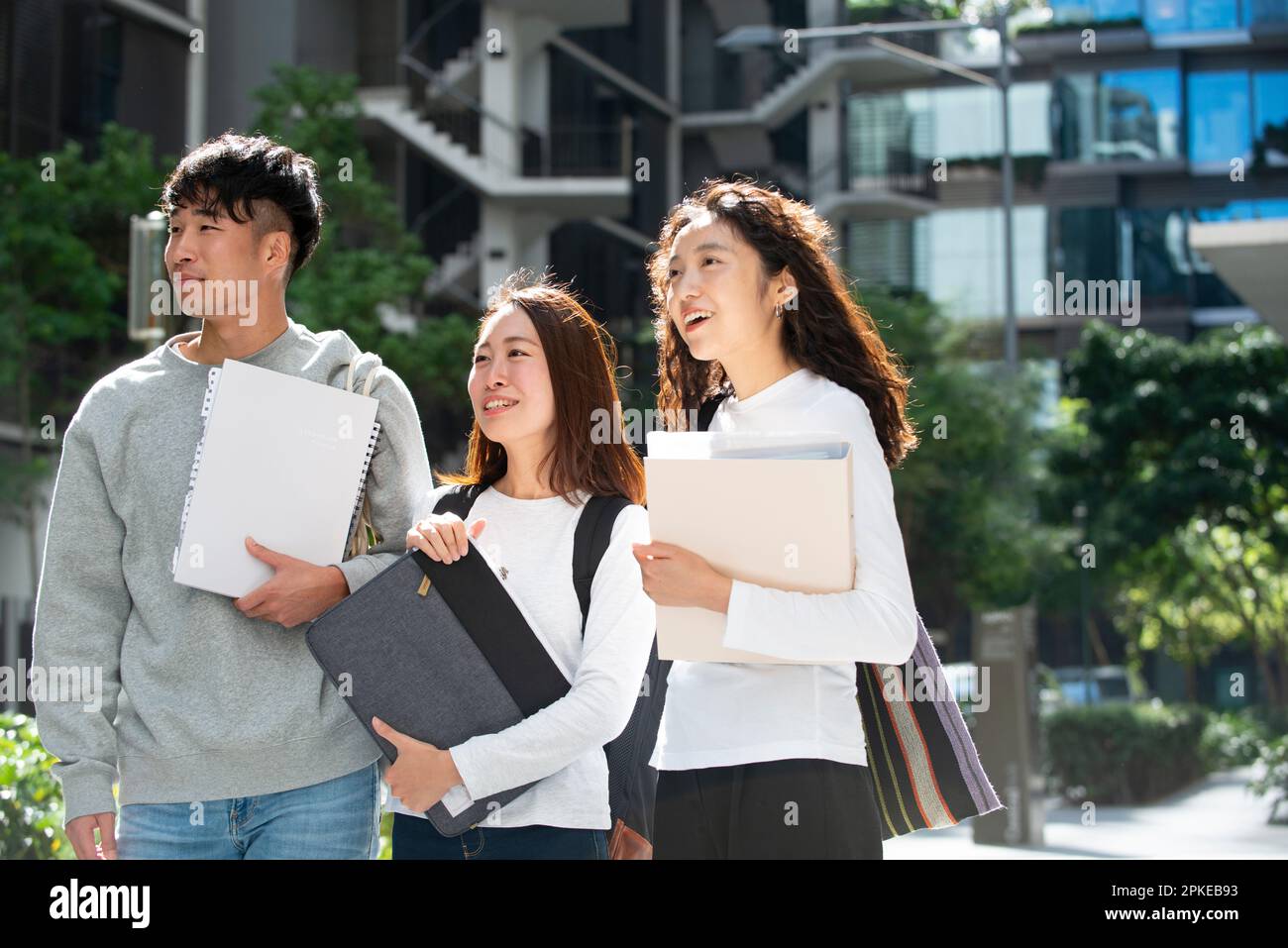 Three students holding files and laughing Stock Photo - Alamy