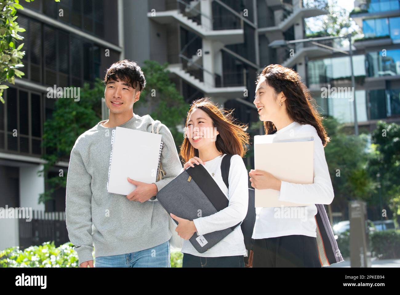Three students holding files and smiling Stock Photo - Alamy
