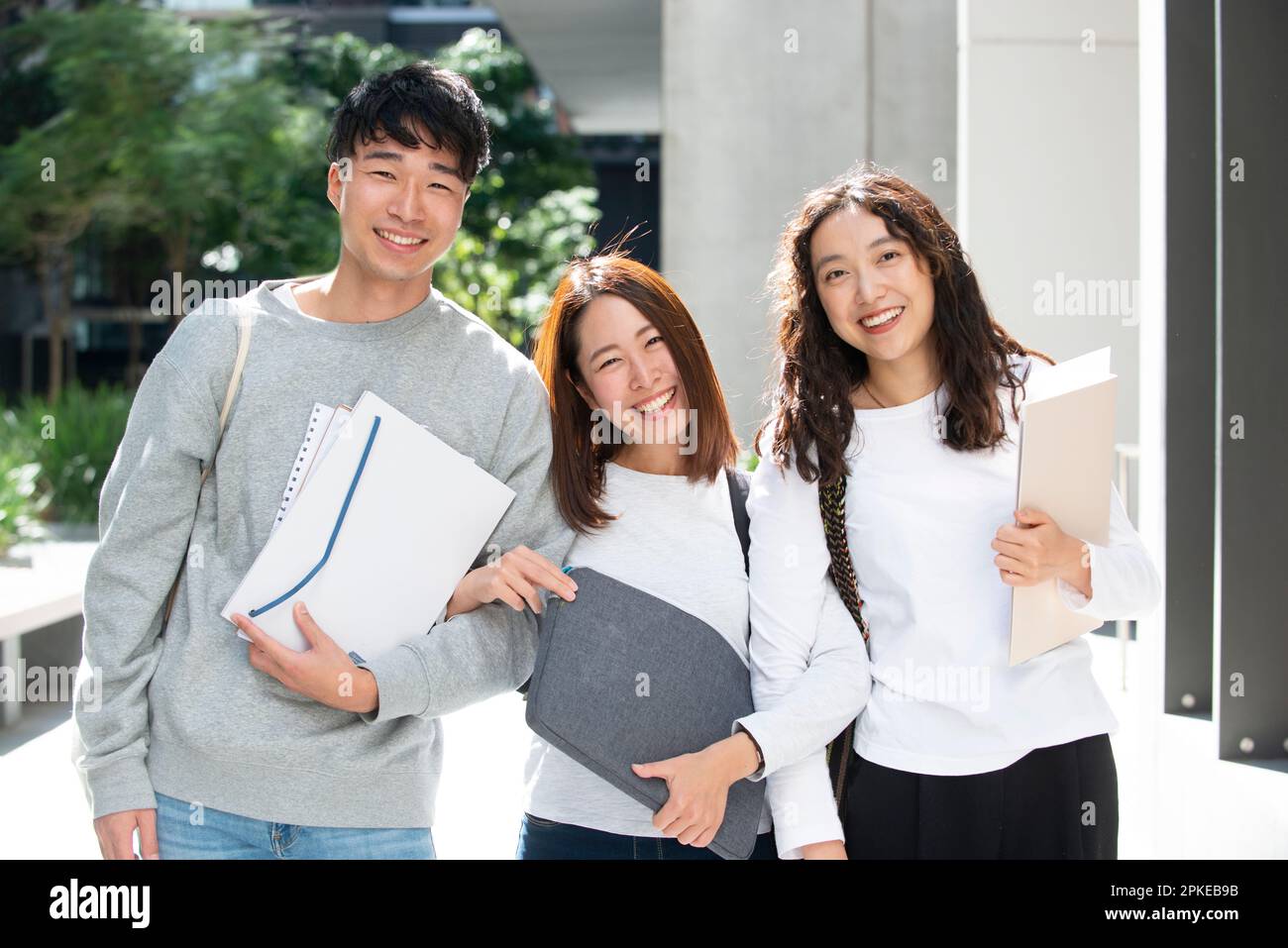 Three students holding files and smiling Stock Photo - Alamy