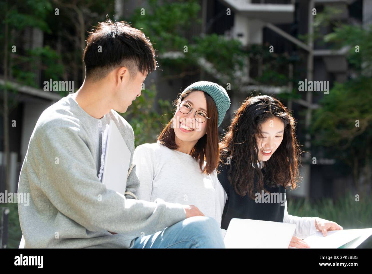 Three students talking with files spread out Stock Photo - Alamy