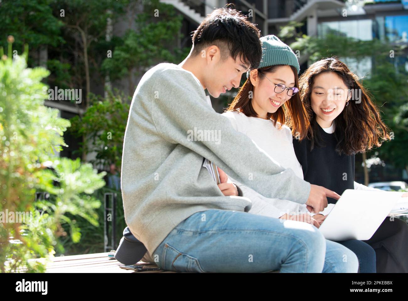 Three students talking with files spread out Stock Photo - Alamy