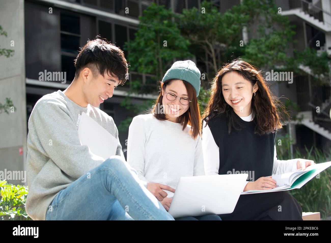 Three students talking with files open Stock Photo - Alamy