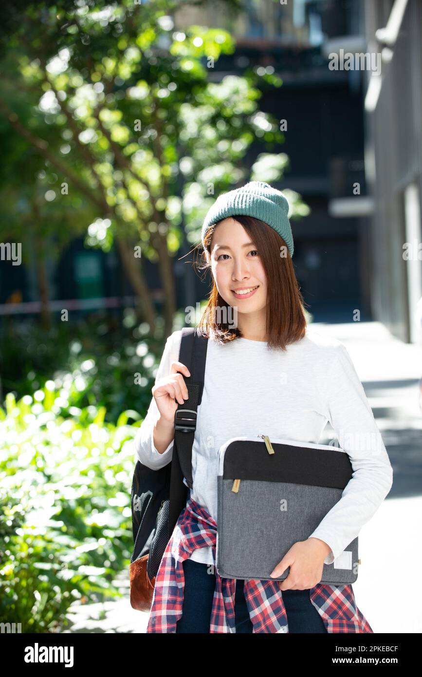 Female student holding a computer pouch and smiling Stock Photo - Alamy