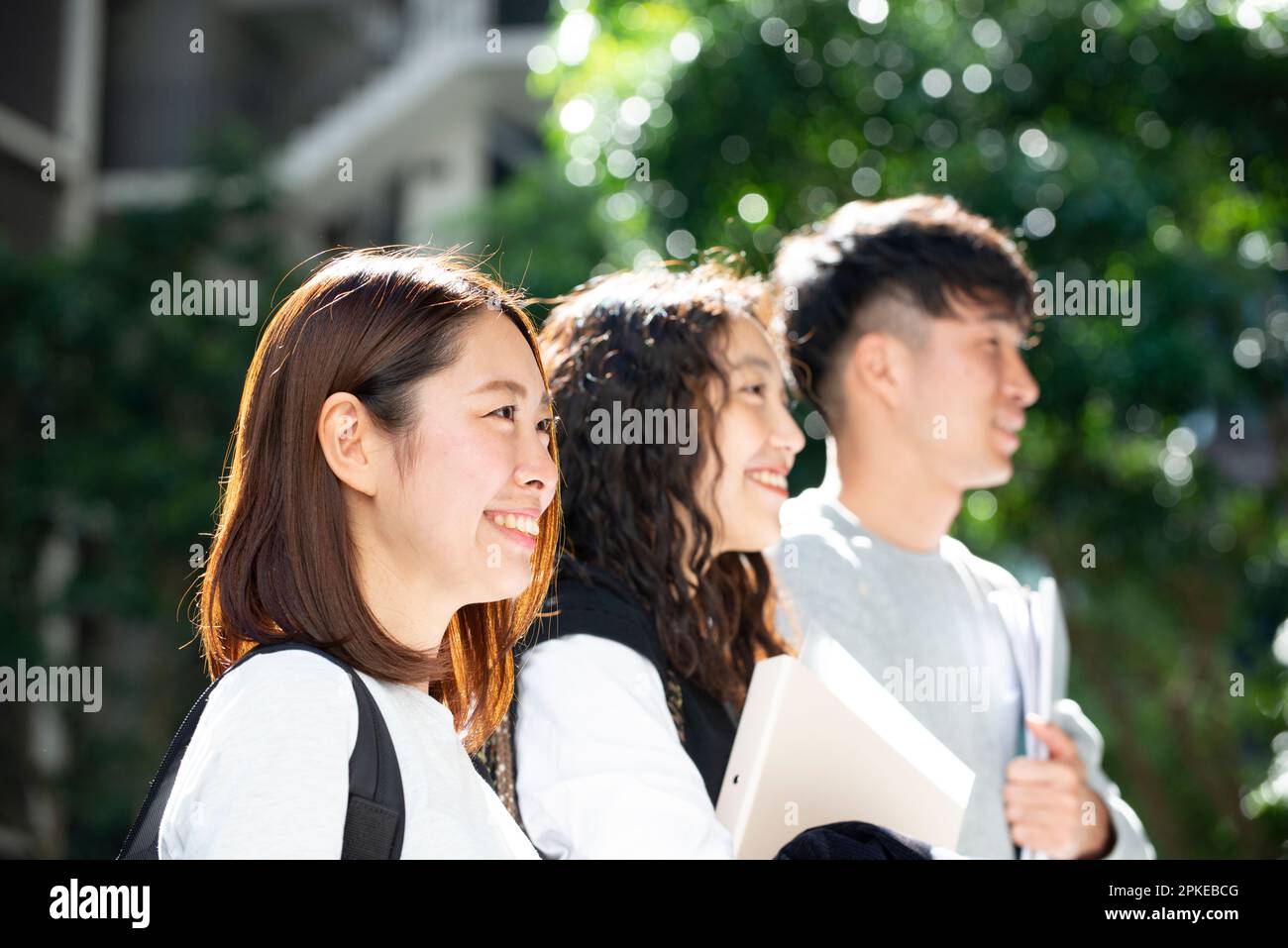 Side view of three young people laughing in a row Stock Photo - Alamy