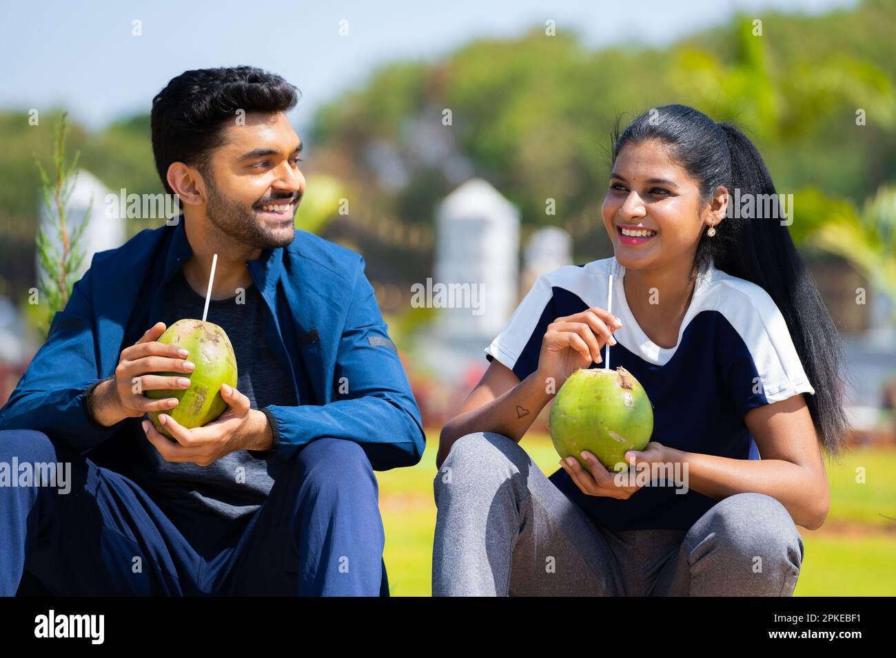 Happy young couple drinking coconut water by talking each other after ...