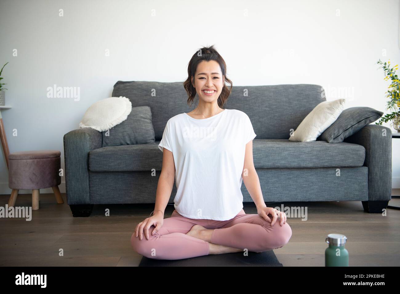 Woman smiling cross-legged on yoga mat Stock Photo - Alamy