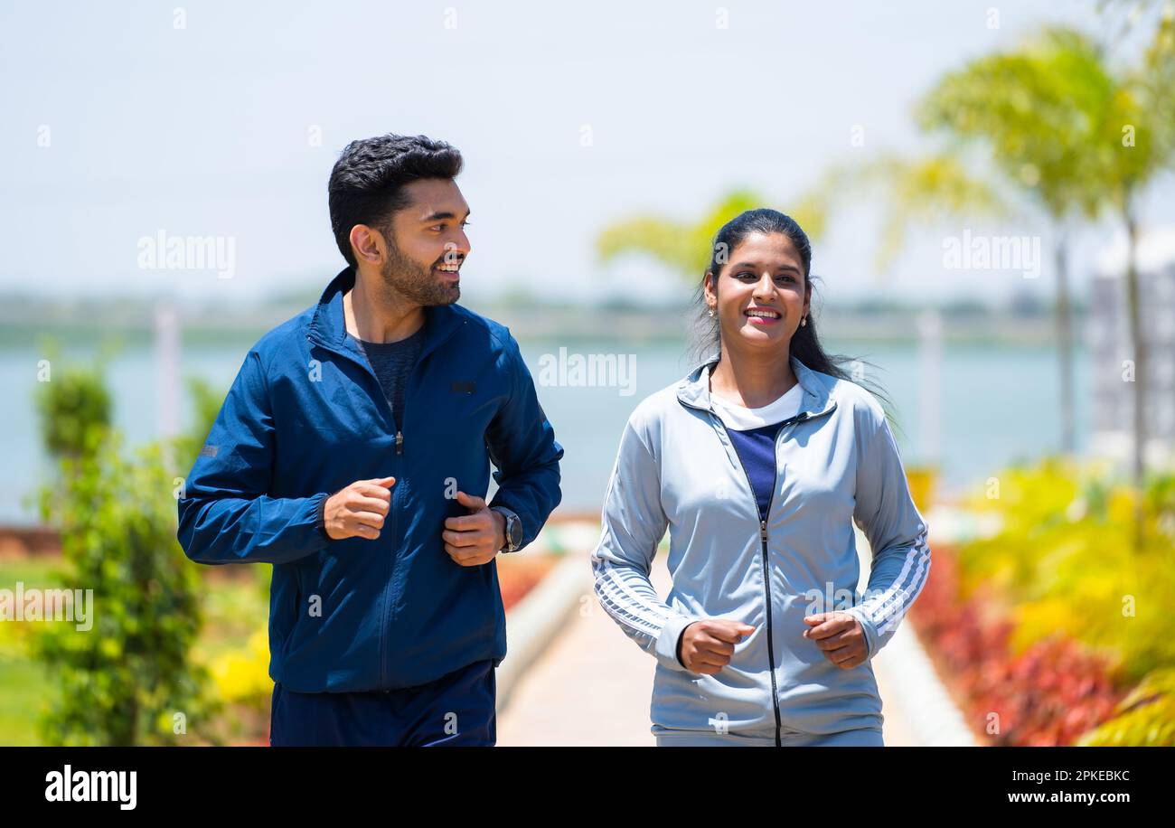Happy Young couple jogging in park while talking each other during ...