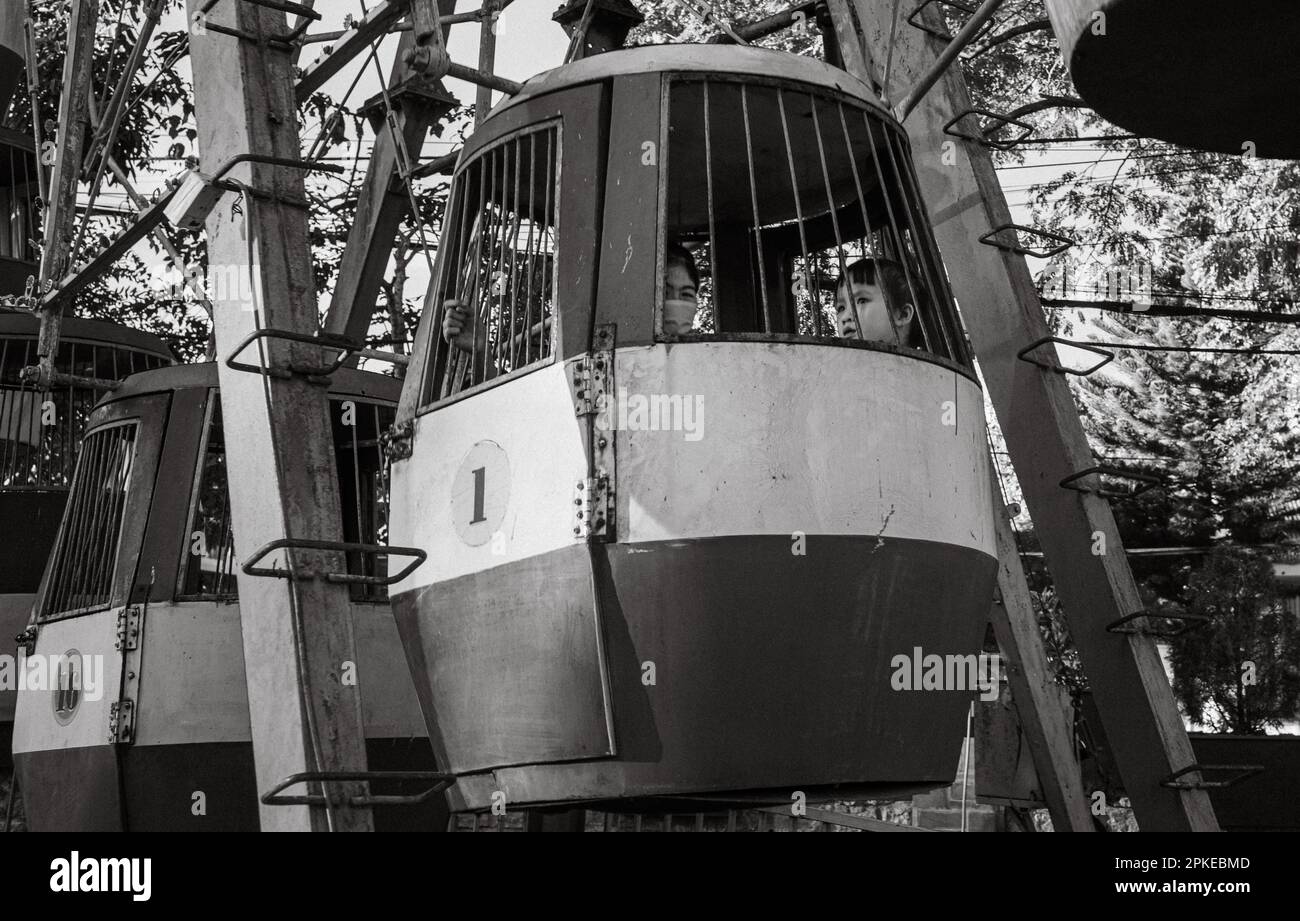 A father and son travel in a caged cabin on a vintage ferris wheel in ...