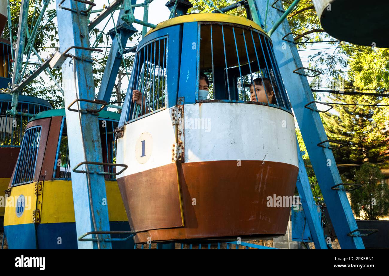 A father and son travel in a caged cabin on a vintage ferris wheel in ...