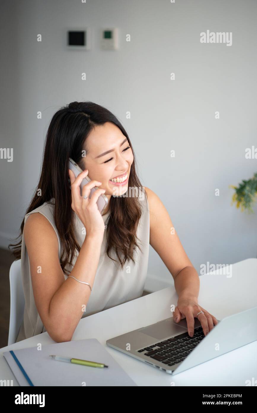 Woman on the phone with computer open Stock Photo - Alamy