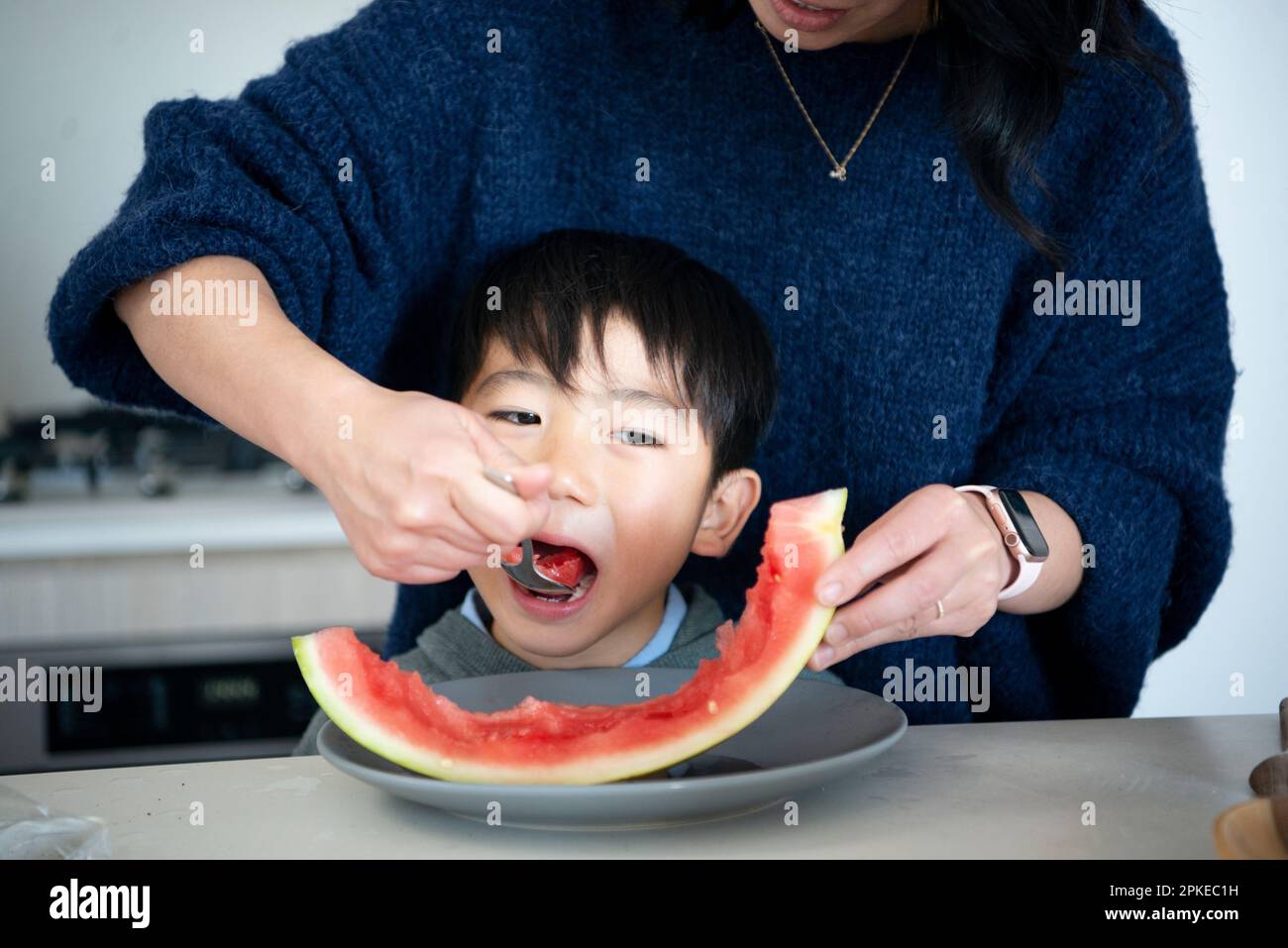 Boy with a watermelon being fed by his mother Stock Photo - Alamy