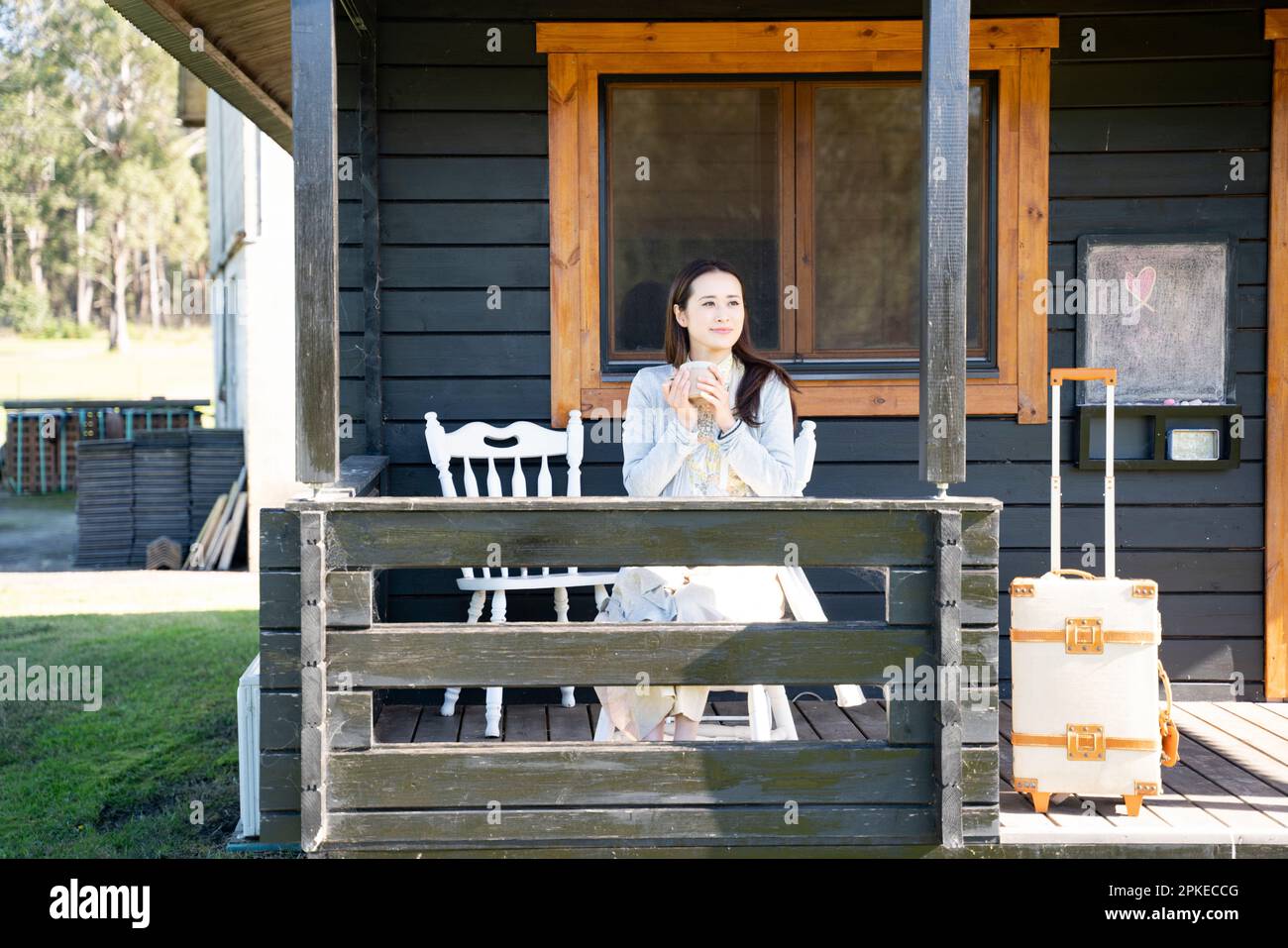 Woman drinking tea on porch of cottage Stock Photo - Alamy