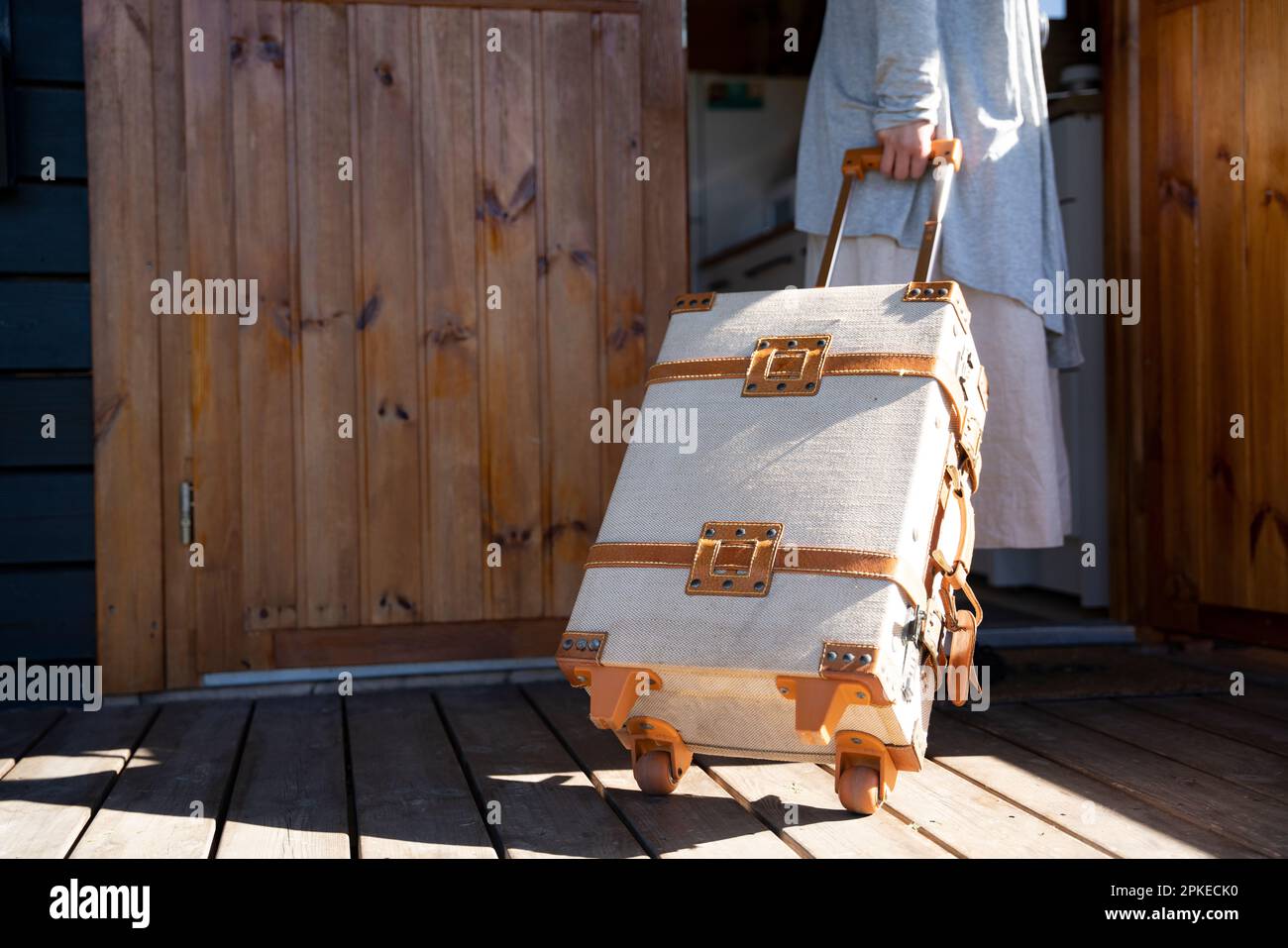 Woman pulling suitcase going into building Stock Photo - Alamy