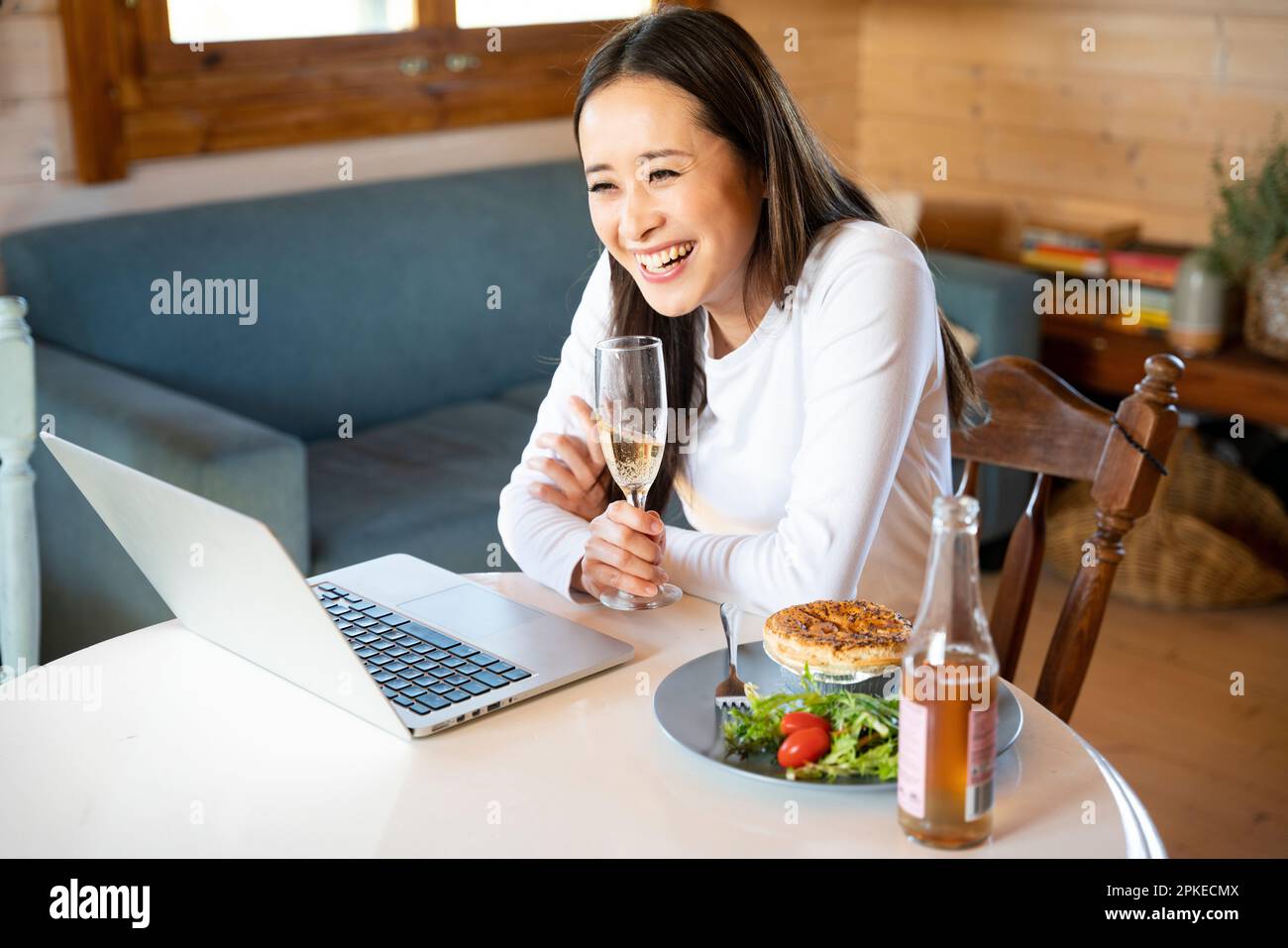 Woman having a remote drinking session with a laptop in front of her ...
