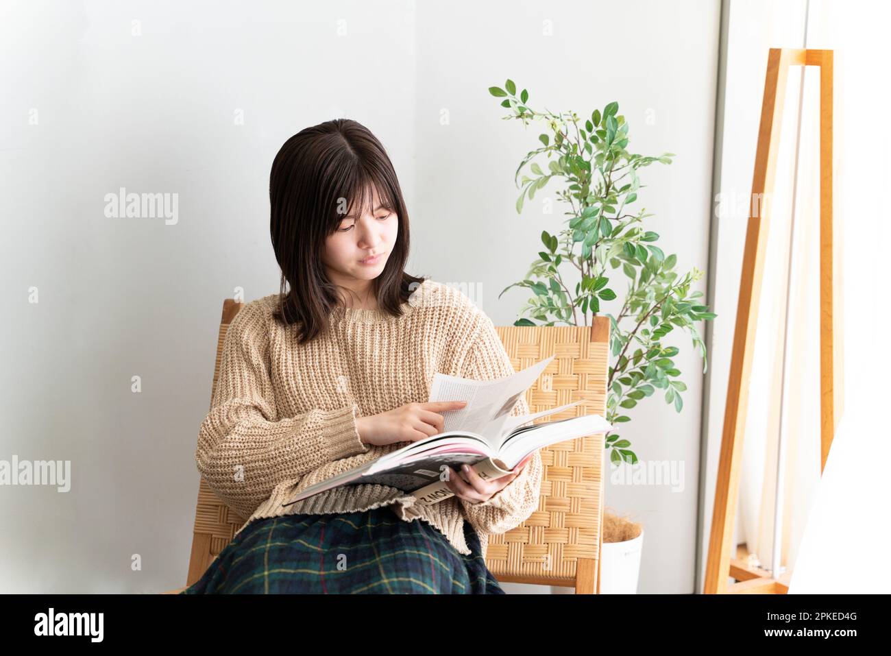 Woman sitting by the window reading a book Stock Photo - Alamy