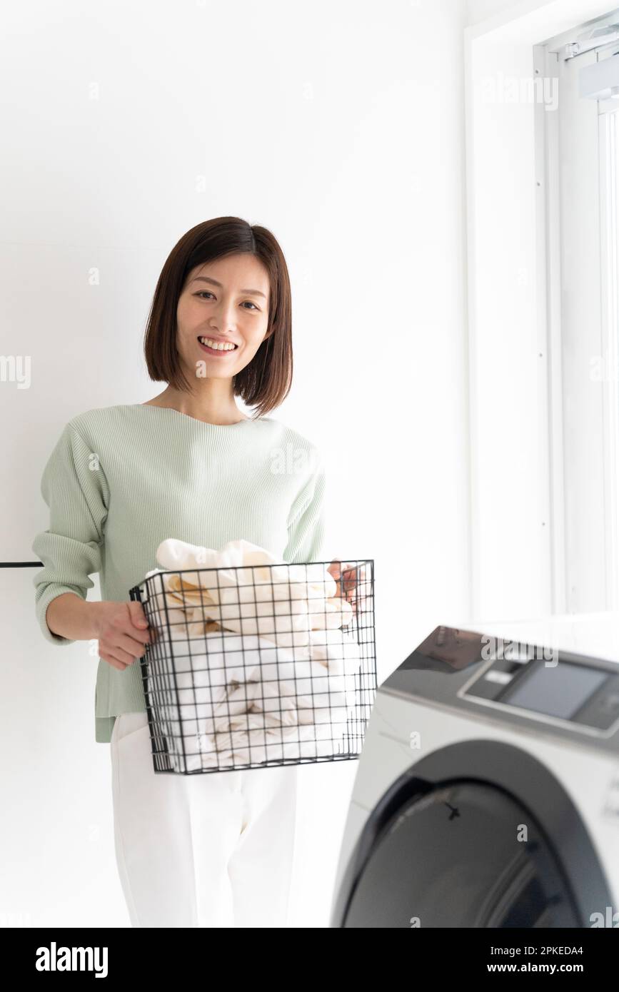 Woman laughing while holding laundry basket Stock Photo - Alamy