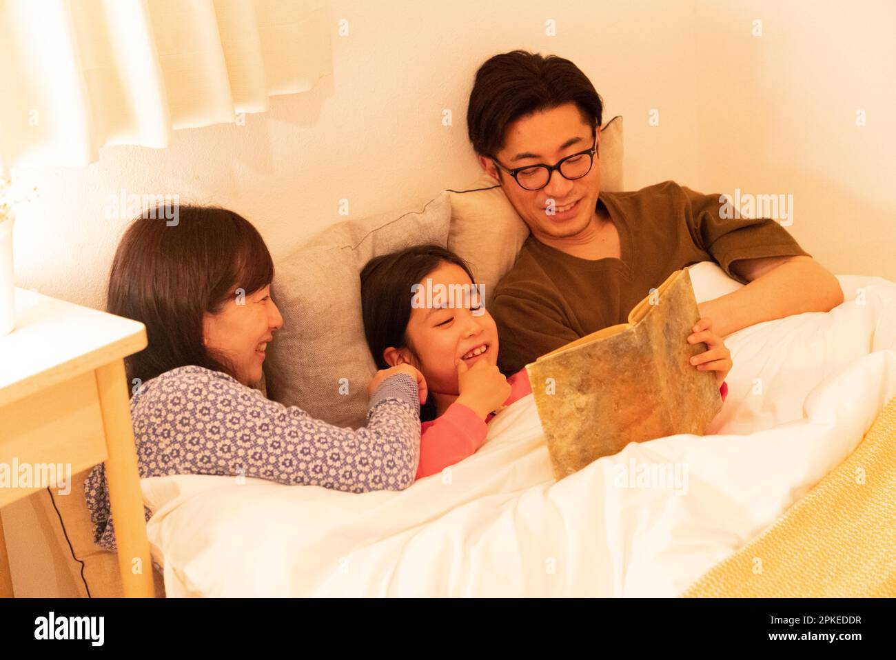 Parent and child of three reading to each other in bed Stock Photo - Alamy