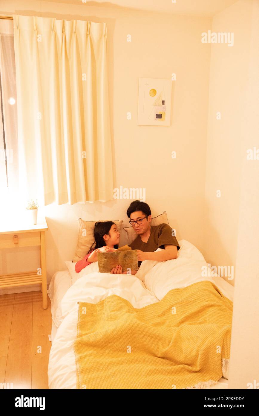 Parent and child reading a book in bed Stock Photo - Alamy