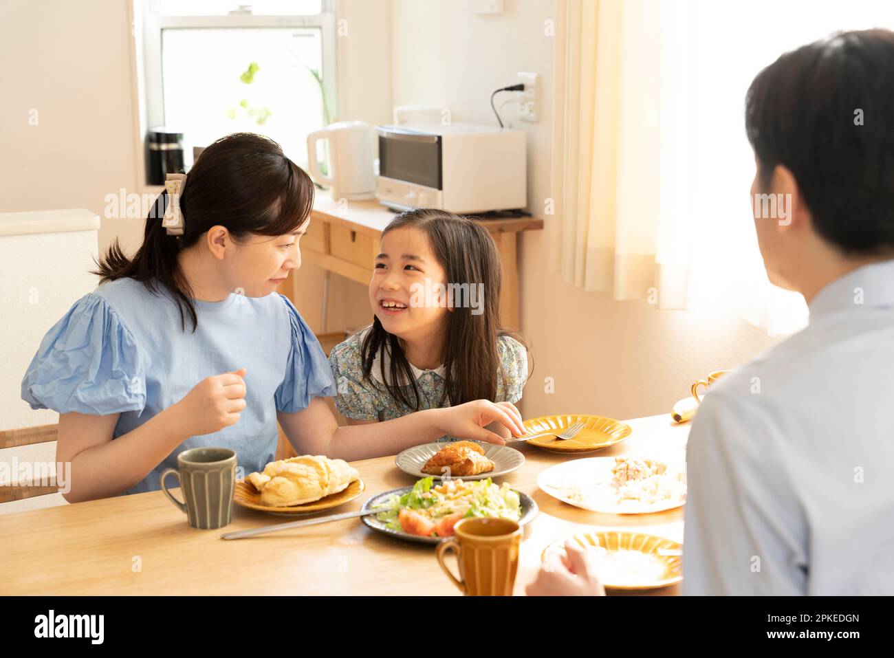Parents and children eating breakfast while talking Stock Photo - Alamy