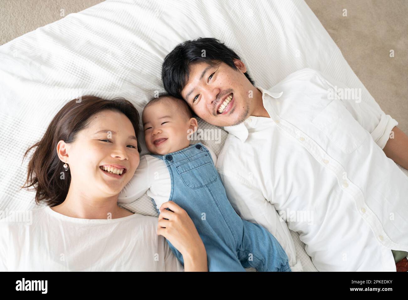 Family lying on bed laughing Stock Photo - Alamy