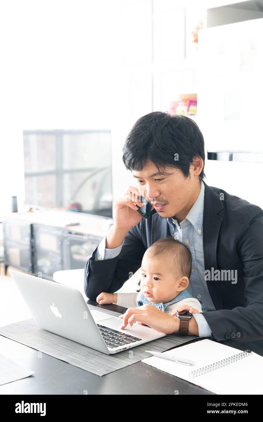 Man talking on the phone while holding baby Stock Photo - Alamy