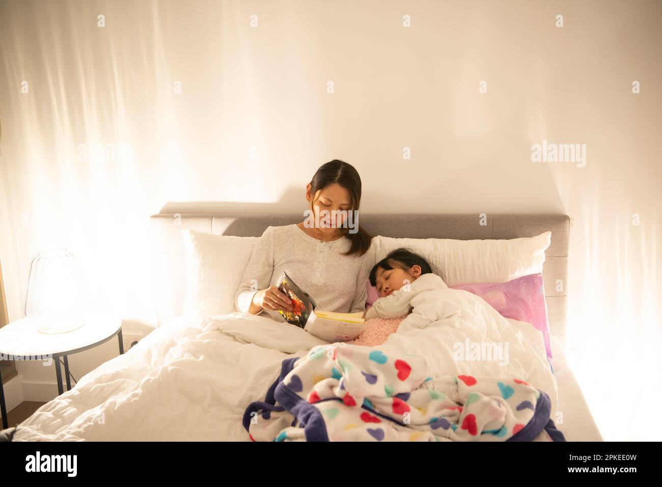 Parent and child reading a book in bed Stock Photo - Alamy