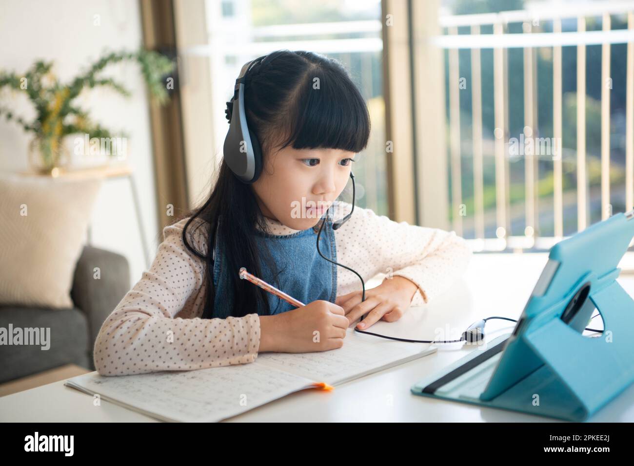 Girl studying in living room with headphones Stock Photo - Alamy