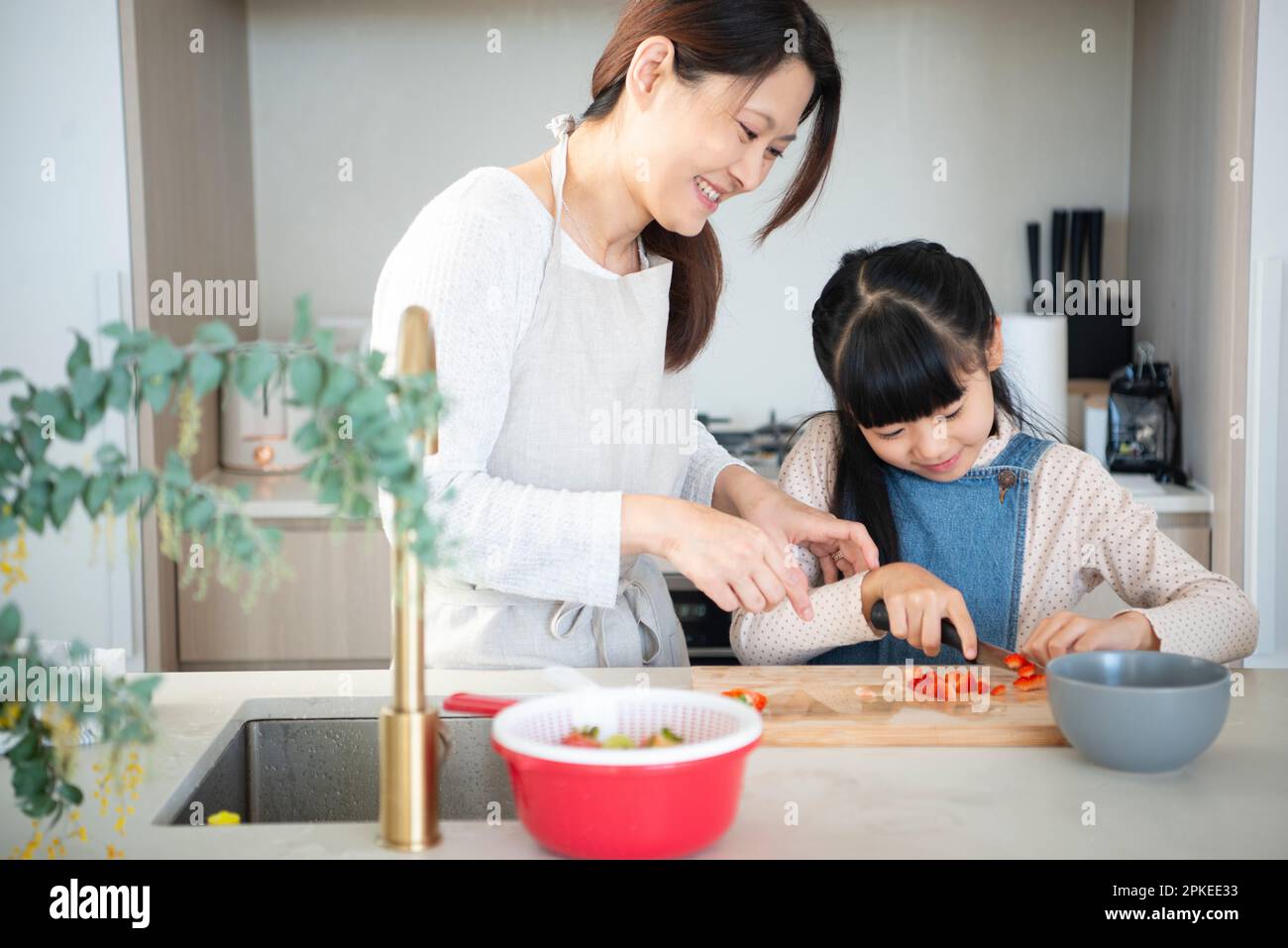 Girl and her mother helping in the kitchen Stock Photo - Alamy