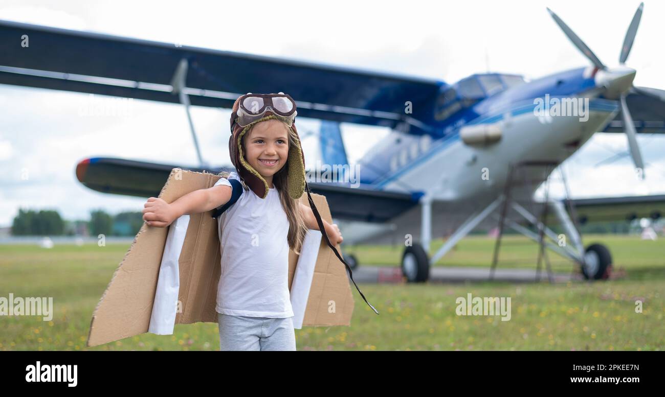 A little girl plays a pilot on the background of a small plane with a ...