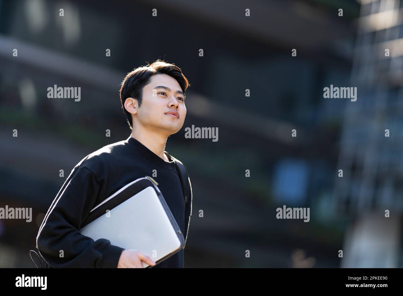 Man holding computer and looking far away Stock Photo - Alamy