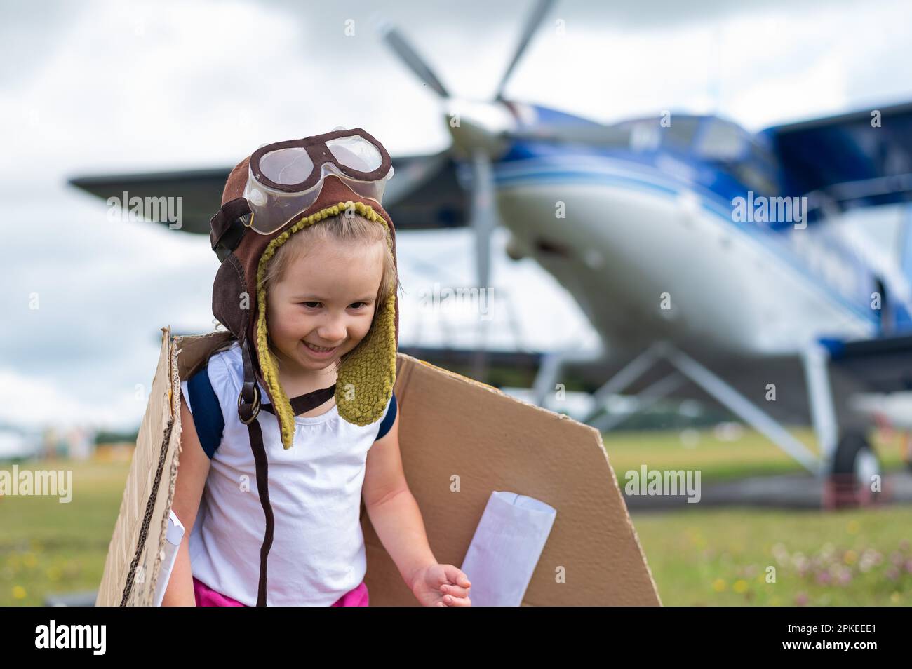 A cute little girl dressed in a cap and glasses of a pilot on the ...