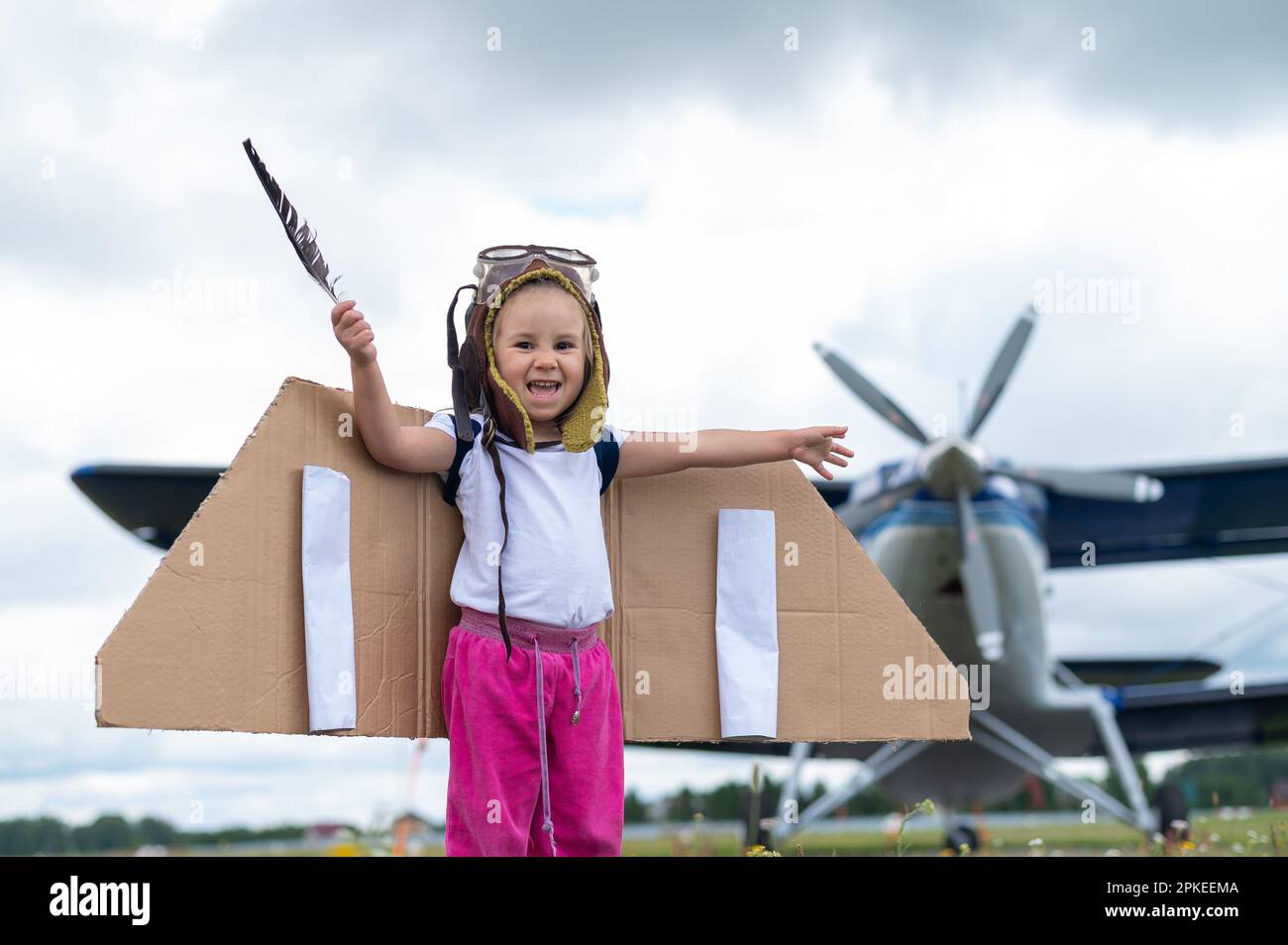 A cute little girl playing on the field by a four-seater private jet ...