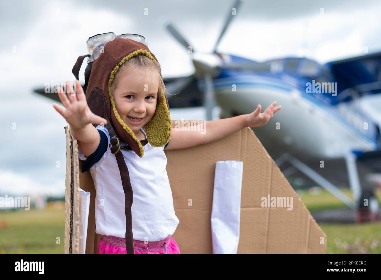A cute little girl dressed in a cap and glasses of a pilot on the ...