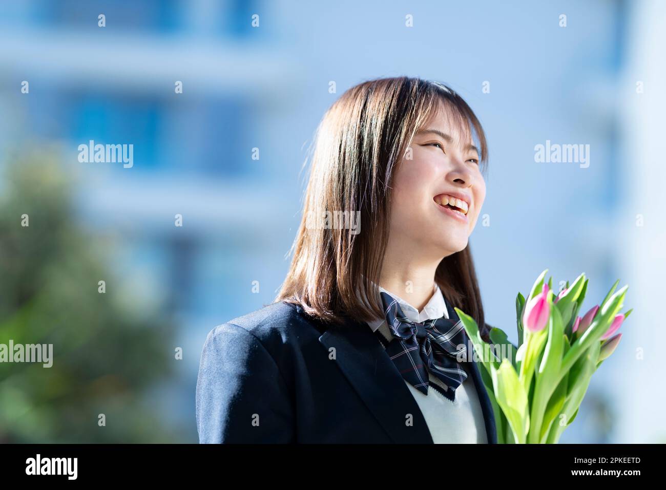 Female student in school uniform holding tulip and laughing Stock Photo ...