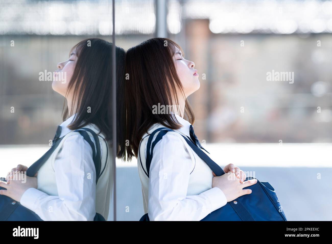 Female student in school uniform leaning over and closing her eyes ...