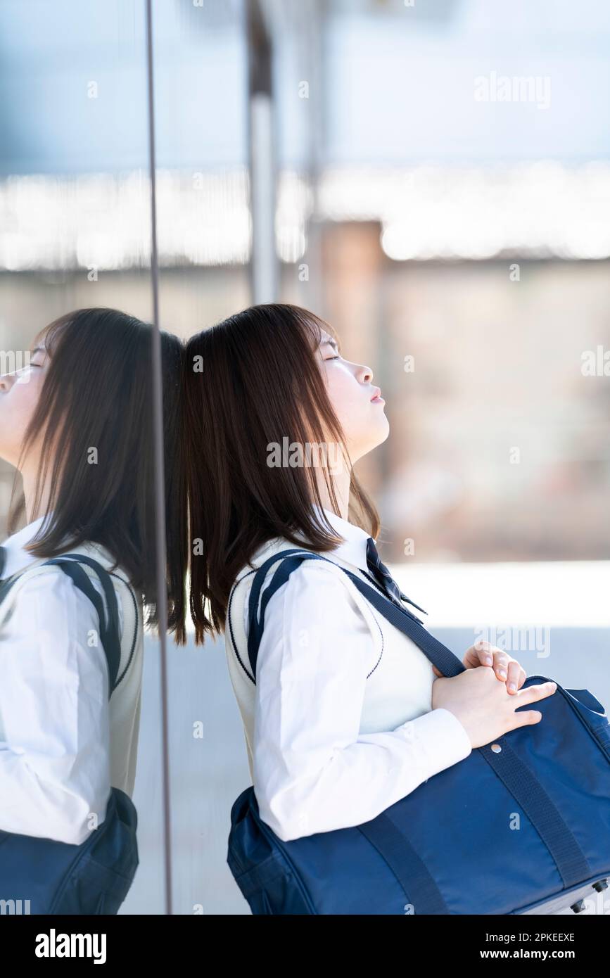Female student in school uniform leaning over and closing her eyes ...