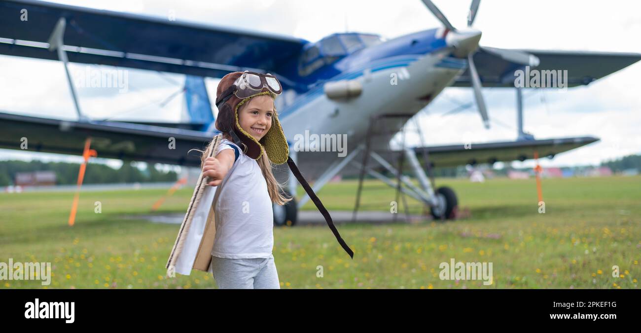 A little girl plays a pilot on the background of a small plane with a ...