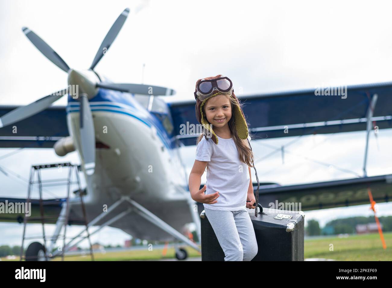 A cute little girl playing on the field by private jet dreaming of ...