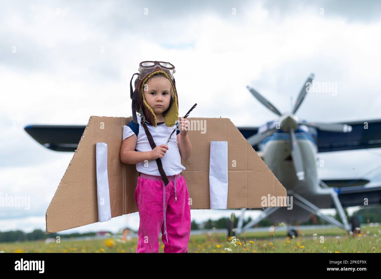 A cute little girl playing on the field by a four-seater private jet ...